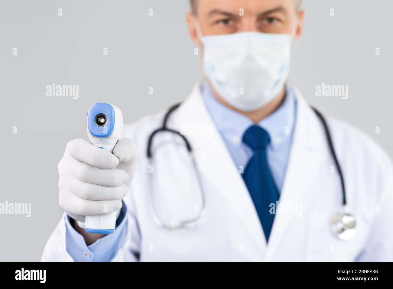 Doctor wearing mask ready to use infrared thermometer Stock Photo - Alamy