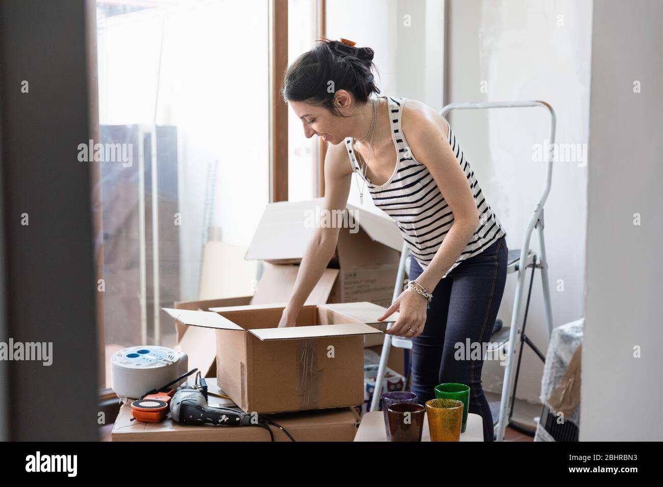 A woman putting items into a cardboard box Stock Photo - Alamy