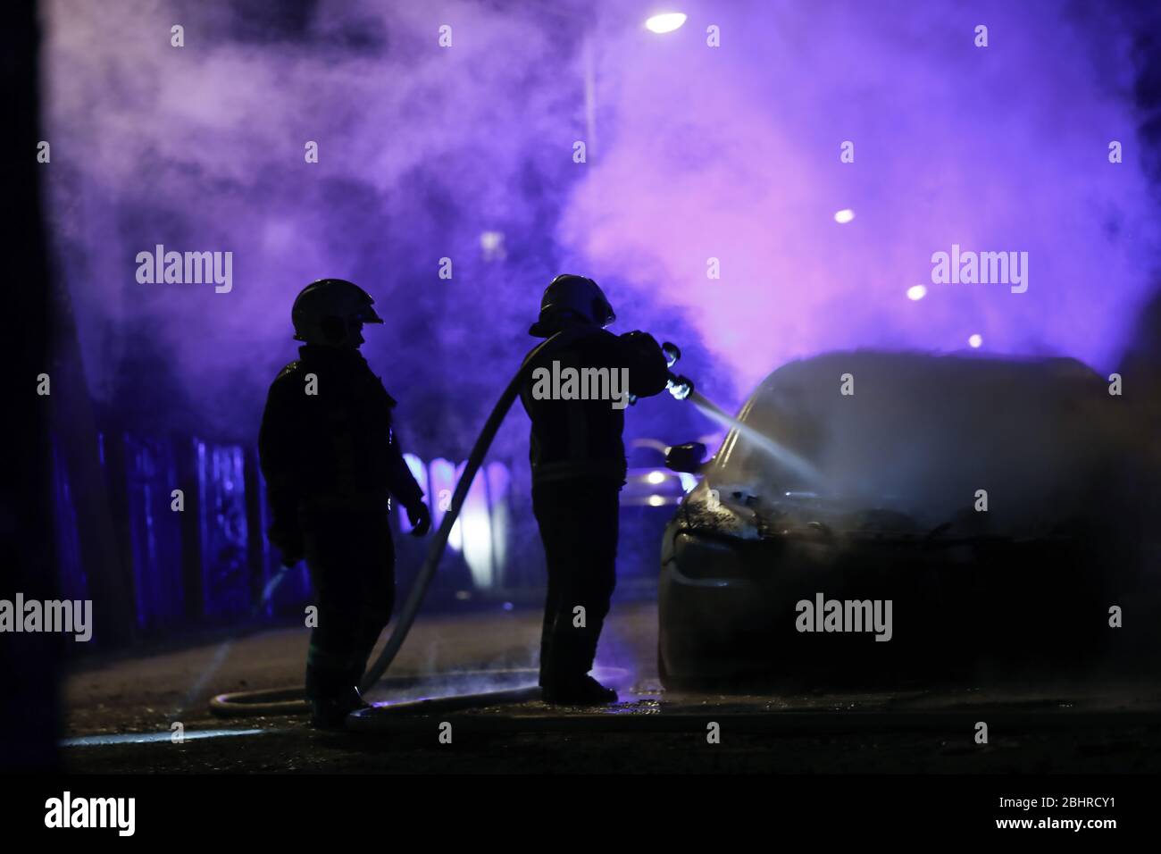 firefighters fighting against the fire in the midnight. Police car in a ...