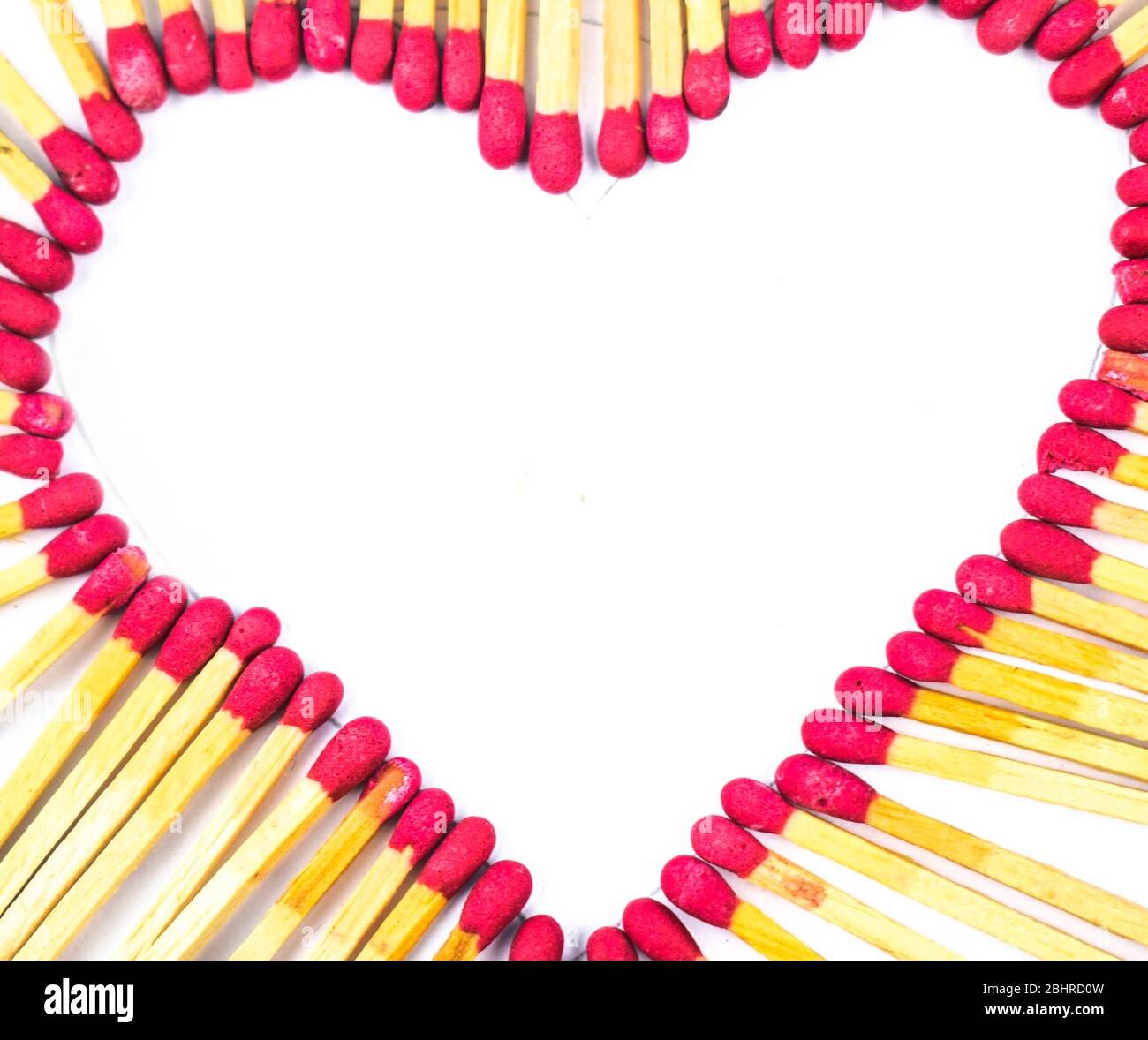 A heart made with red colored match sticks in front of a white isolated ...