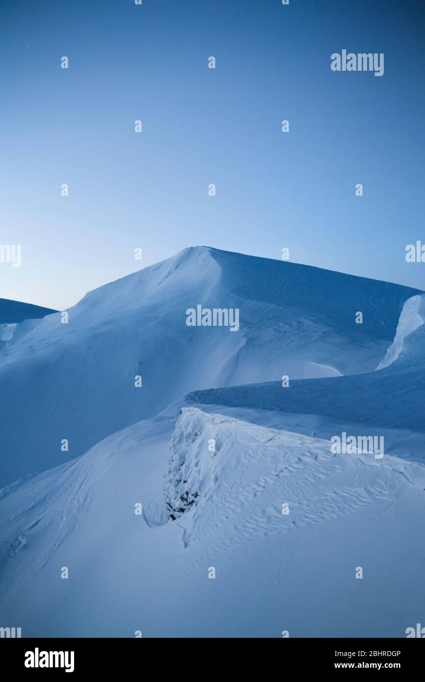 View of a snowy mountain at dusk, smooth snow fields without tracks ...
