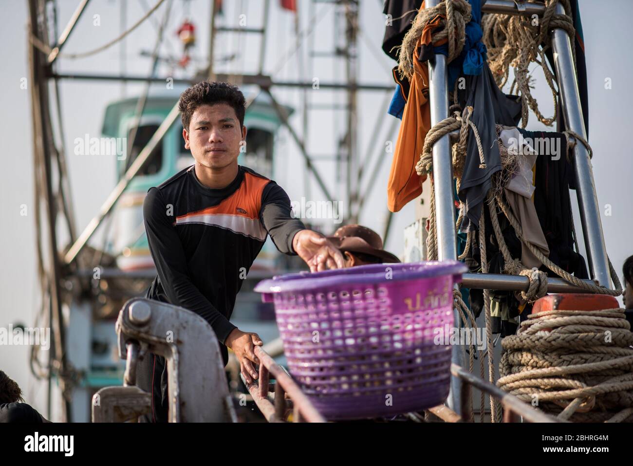 A local man unloading a fish boat at the Samut Sakhon pier in Bangkok ...