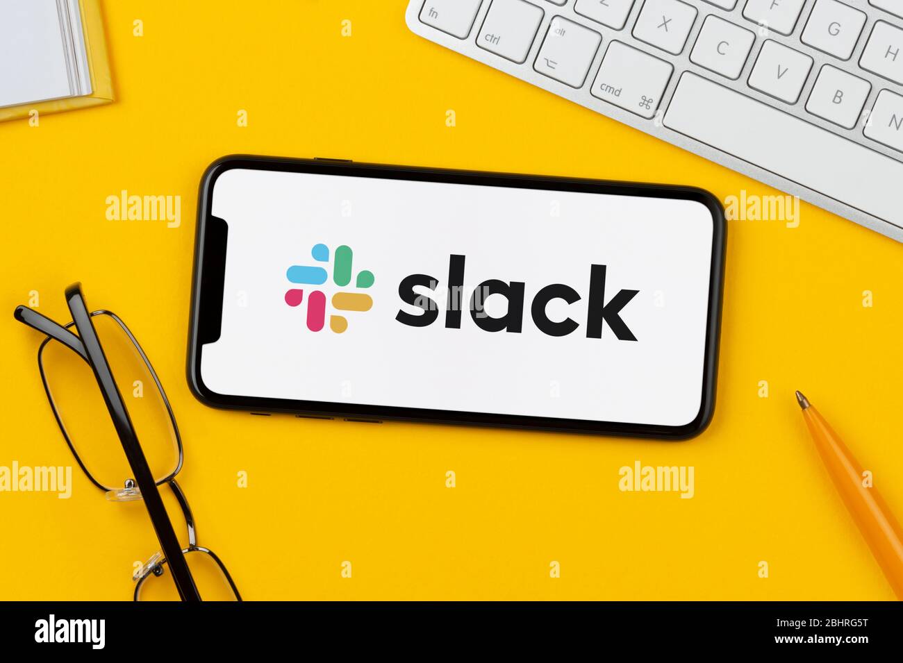 A smartphone showing the Slack logo rests on a yellow background along ...