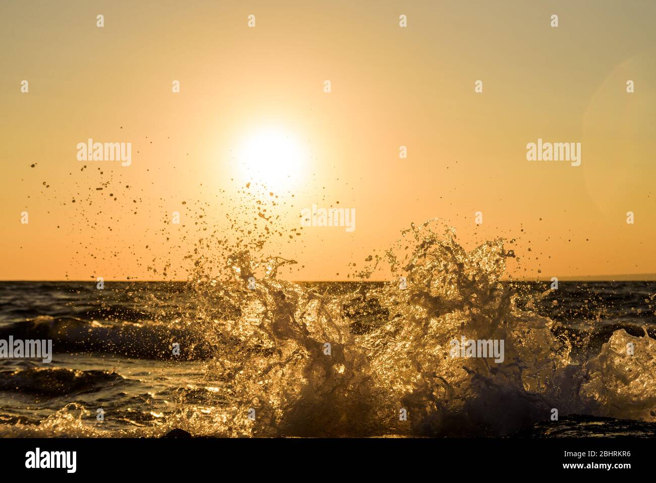 Sunset seascape with rocky beach and crashing waves. Sea water waves ...