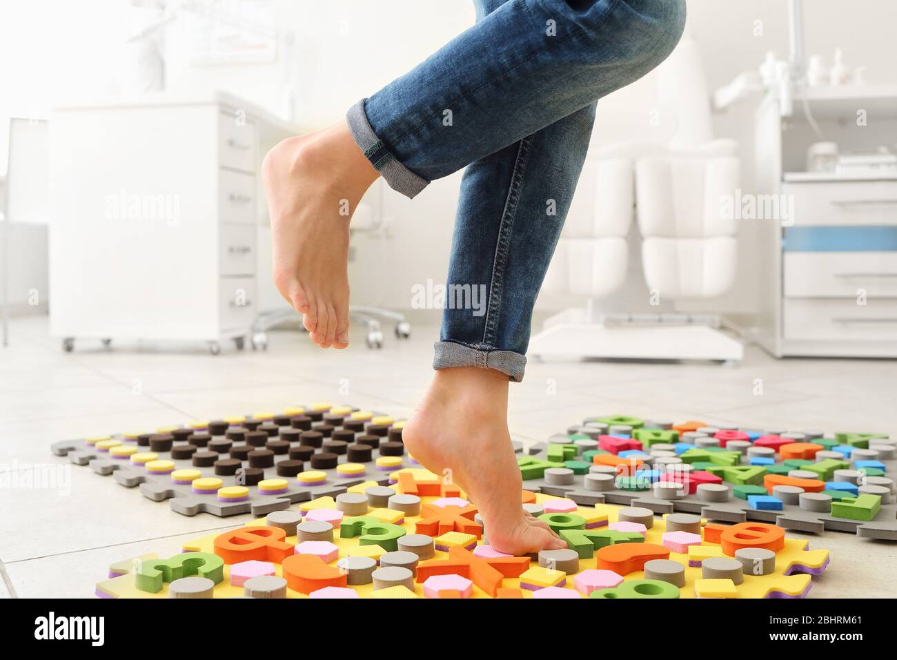 Child flatfoot treatment using special massage carpet.Little girl on ...