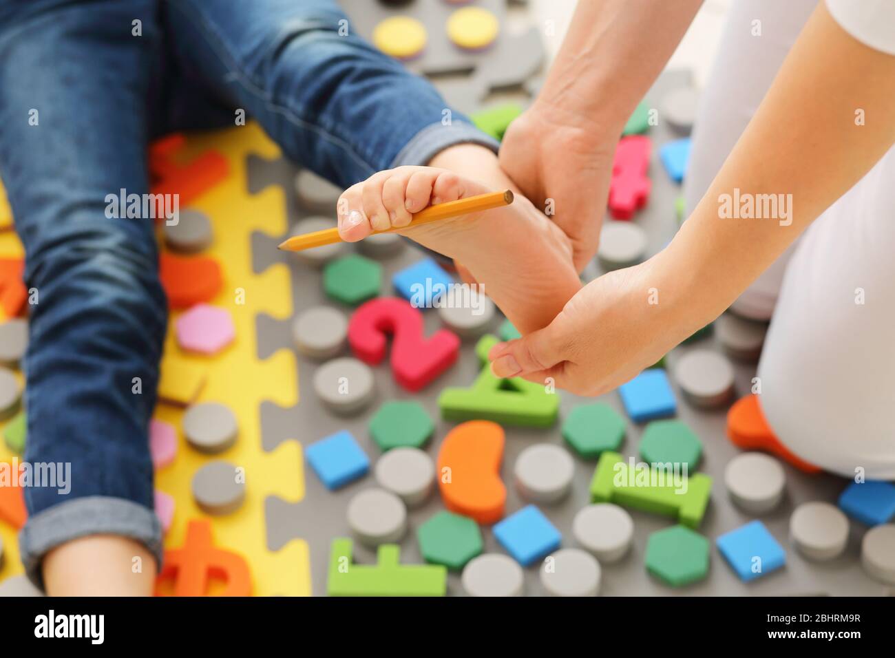 Child flatfoot treatment using special massage carpet.Little girl on ...