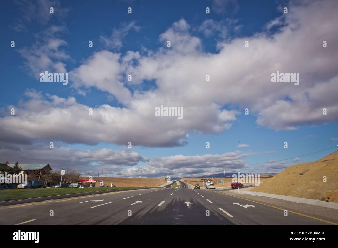 Asphalt road and bright blue sky with fluffy clouds . Empty desert ...