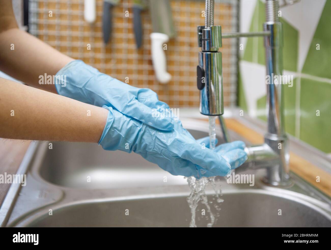 Woman in gloves washing hands before cooking in the kitchen Stock Photo ...