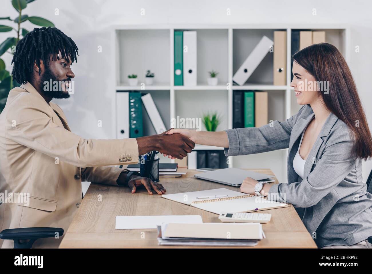 African american recruiter and employee shaking hands, looking at each ...