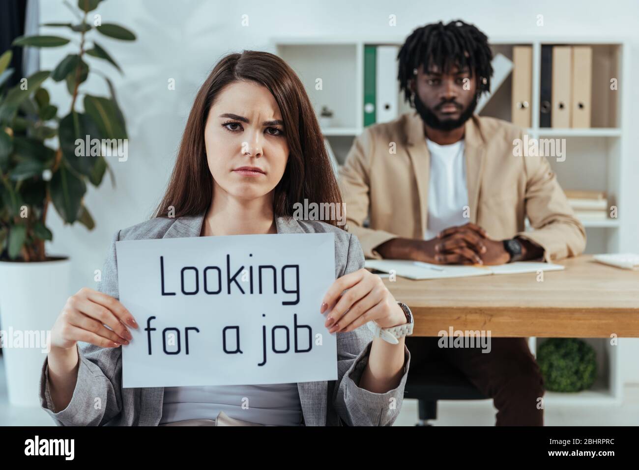 Worried employee showing placard with looking for a job lettering and ...