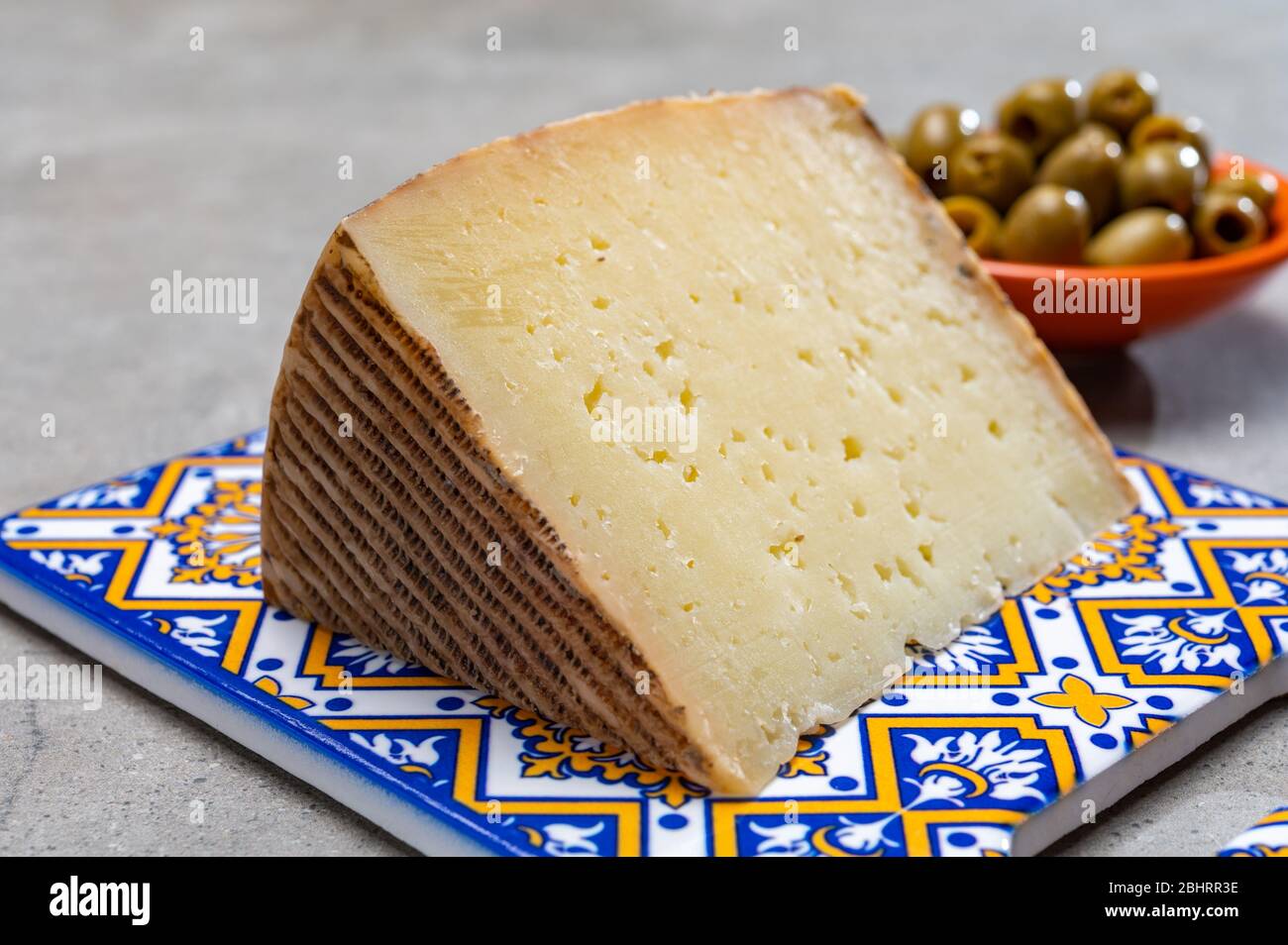 Spanish cheese manchego made from sheep milk with green olives close up ...