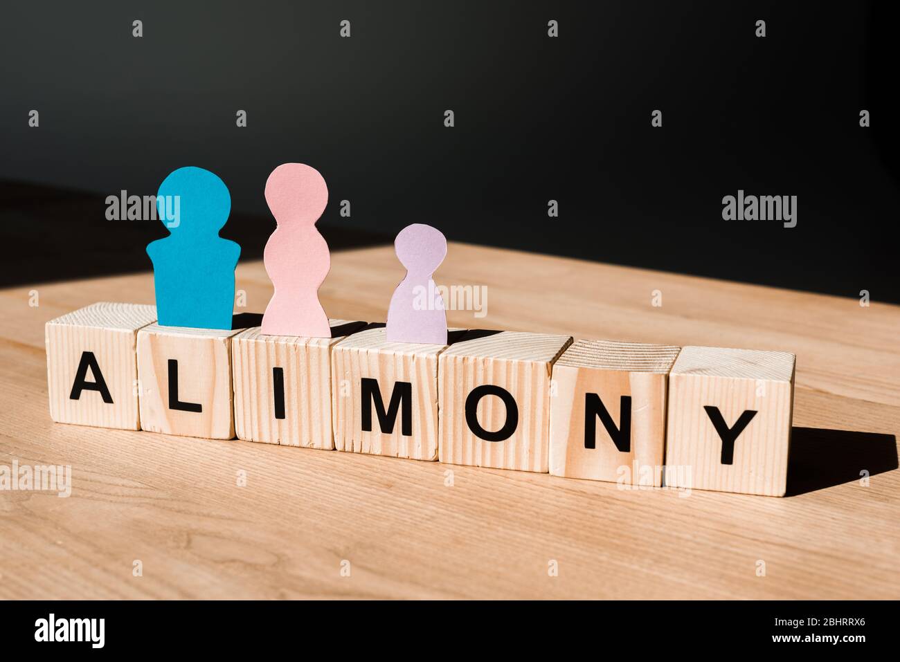 wooden blocks with alimony lettering near family paper people on black ...