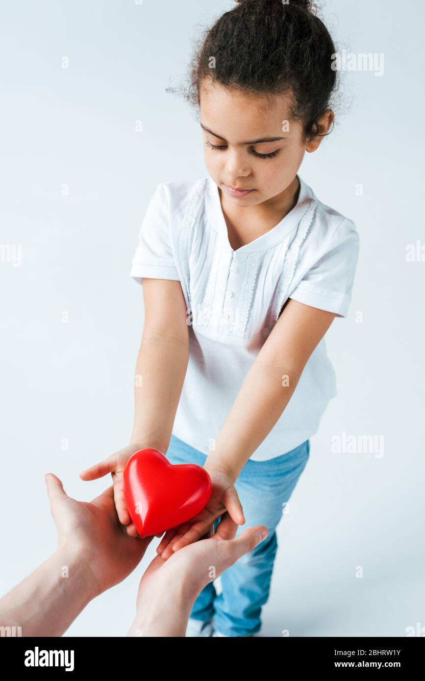 father and adopted african american kid holding red heart on white ...