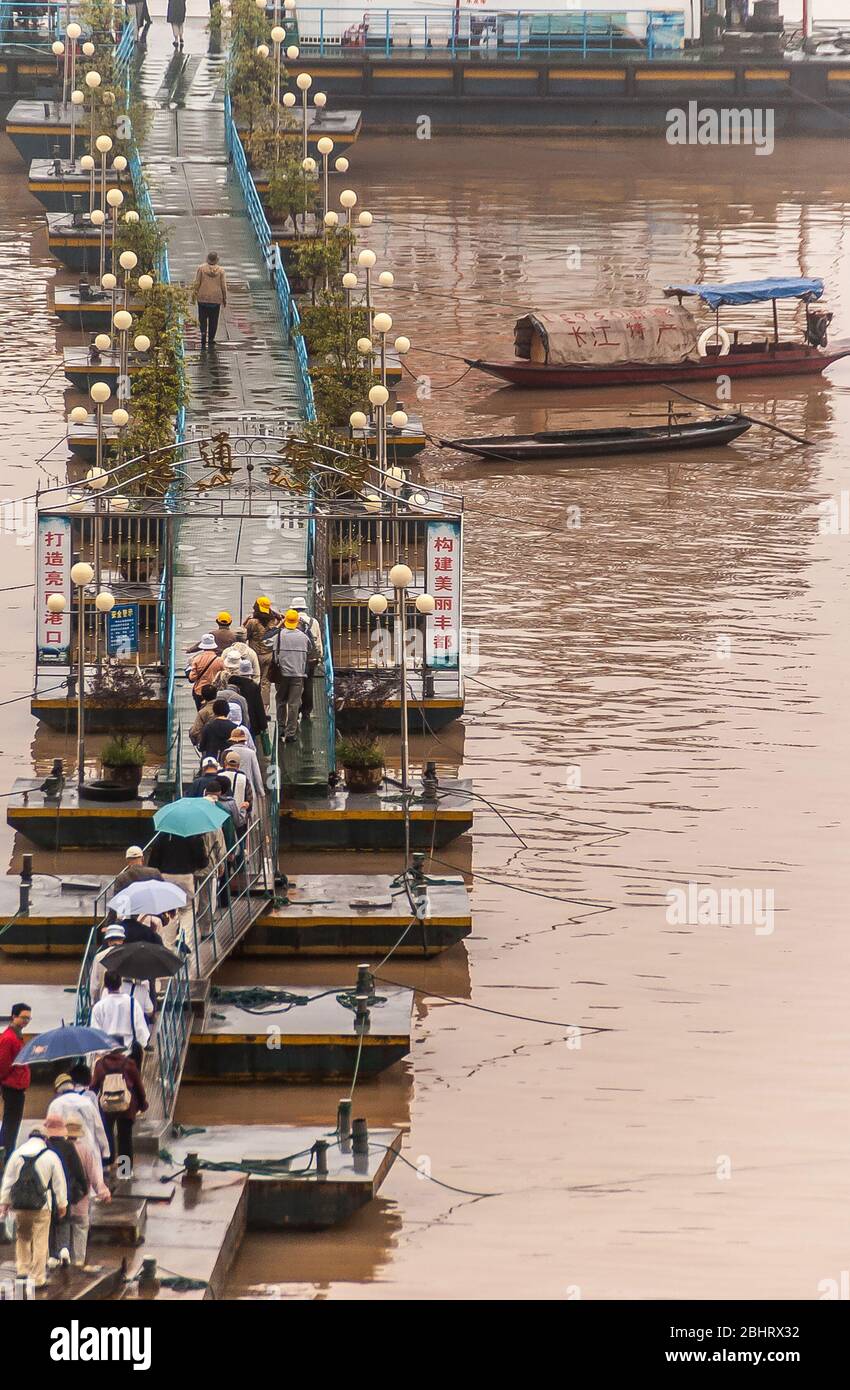 Fengdu, China - May 8, 2010: People walking on narrow pontoon bridge to ...