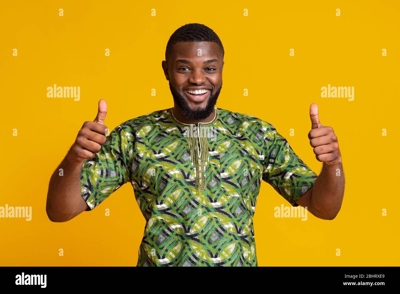 Happy black guy in green african shirt showing thumbs up Stock Photo ...
