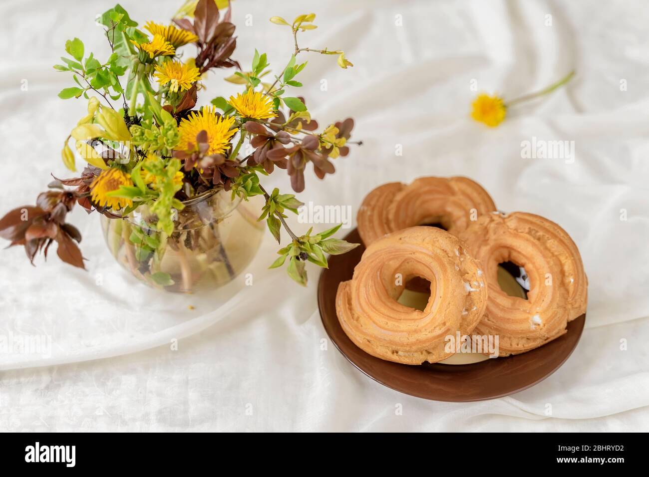 Three eclair rings on saucer, light background, next to spring flowers ...