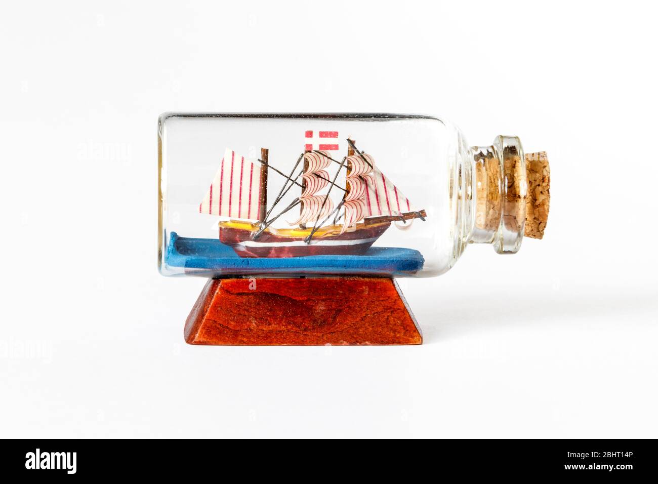 A tiny model sailing ship in a small glass bottle, sealed with a cork ...