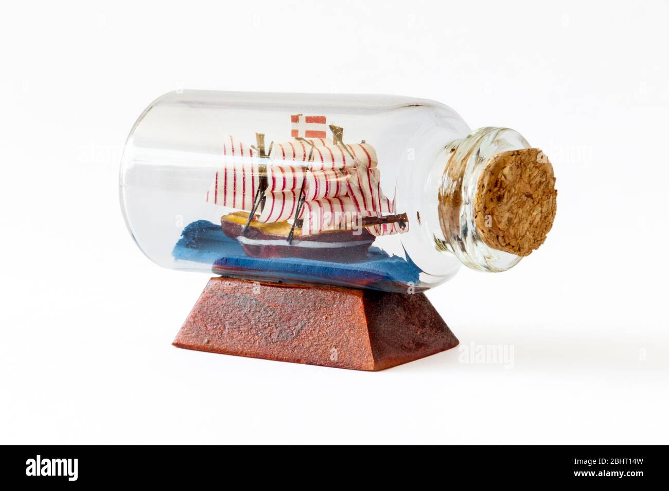 A tiny model sailing ship in a small glass bottle, sealed with a cork ...
