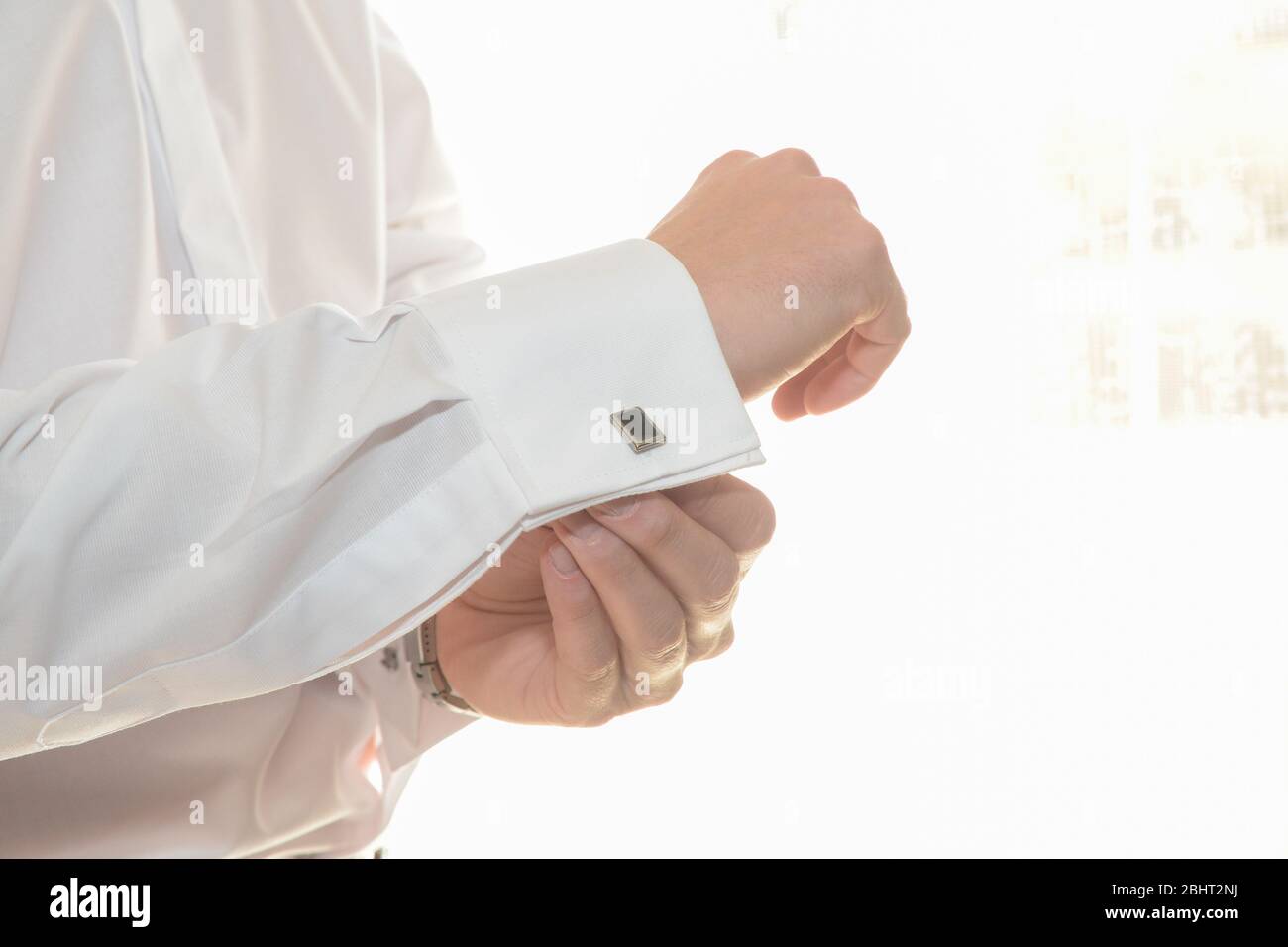 Closeup of the arm of a man who is putting a nice cufflink on the cuff ...