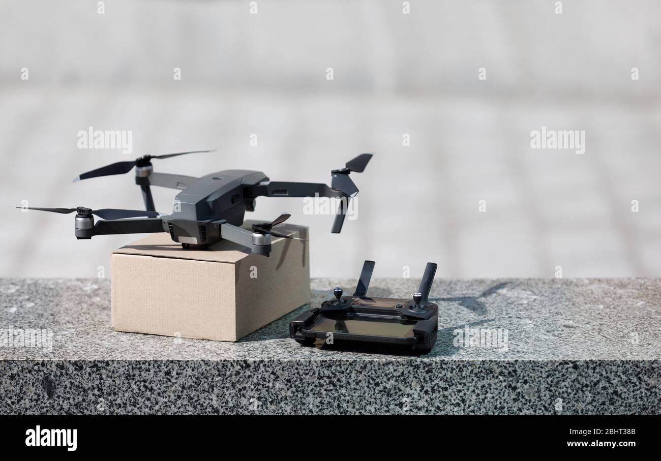 Modern drone with cardboard parcel and remote control Stock Photo - Alamy