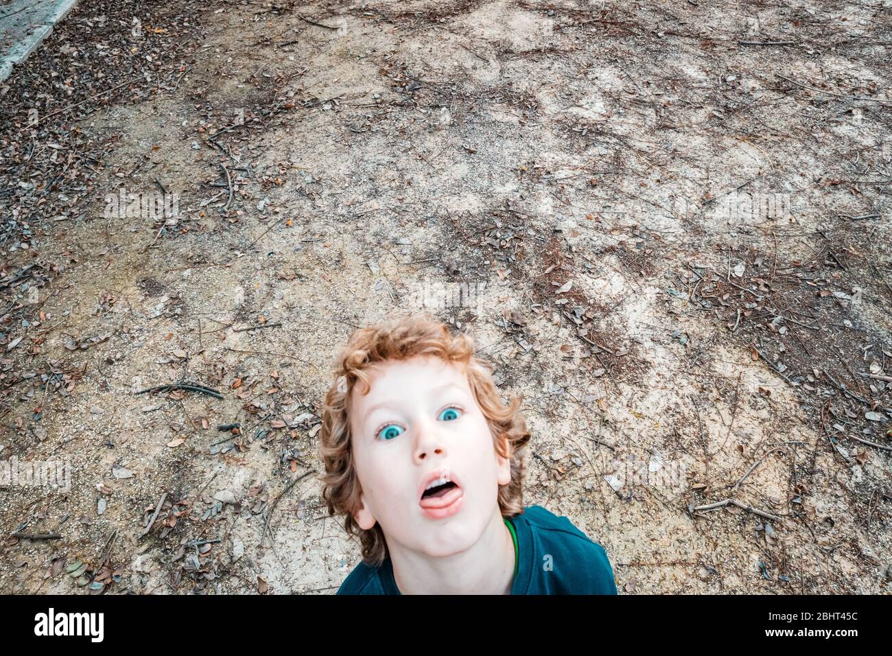 Blond boy making funny gestures and faces photographed from above with ...