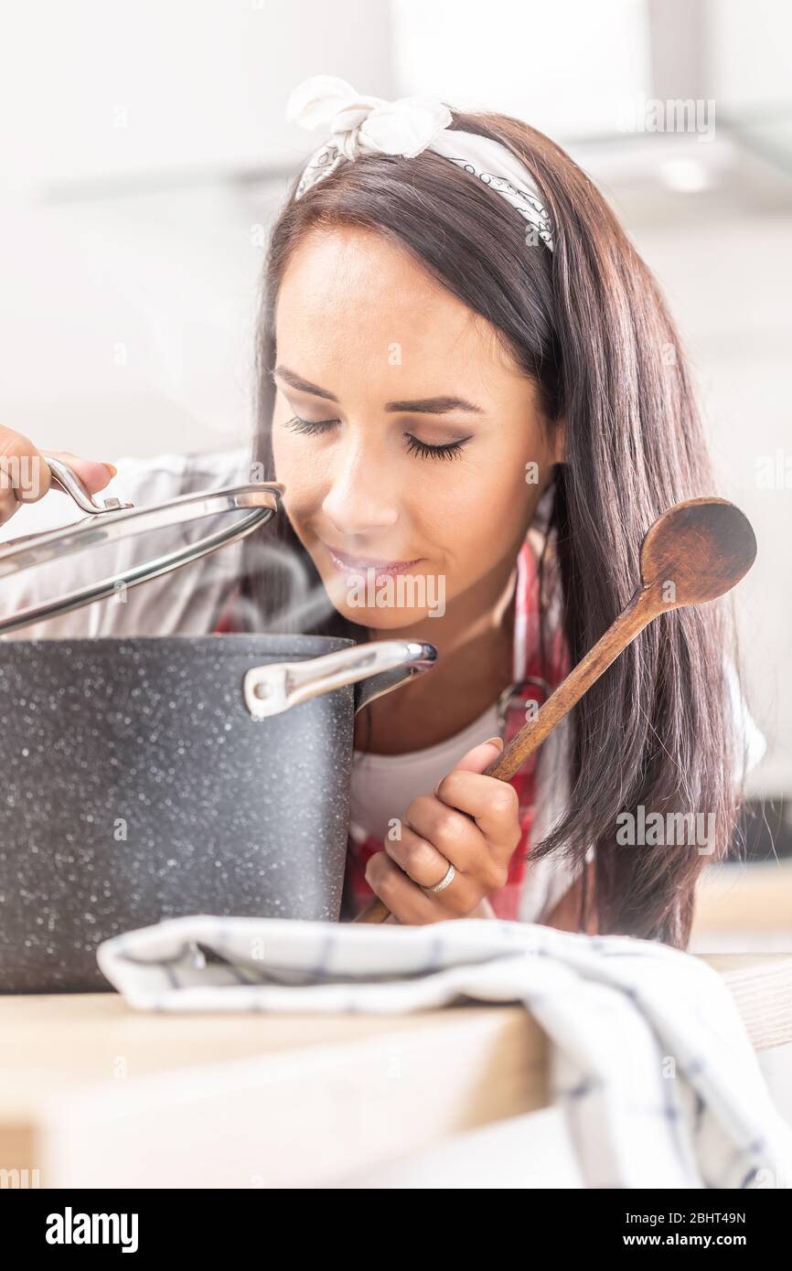 Female with closed eyes smelling freshly cooked food from a cooking pot ...