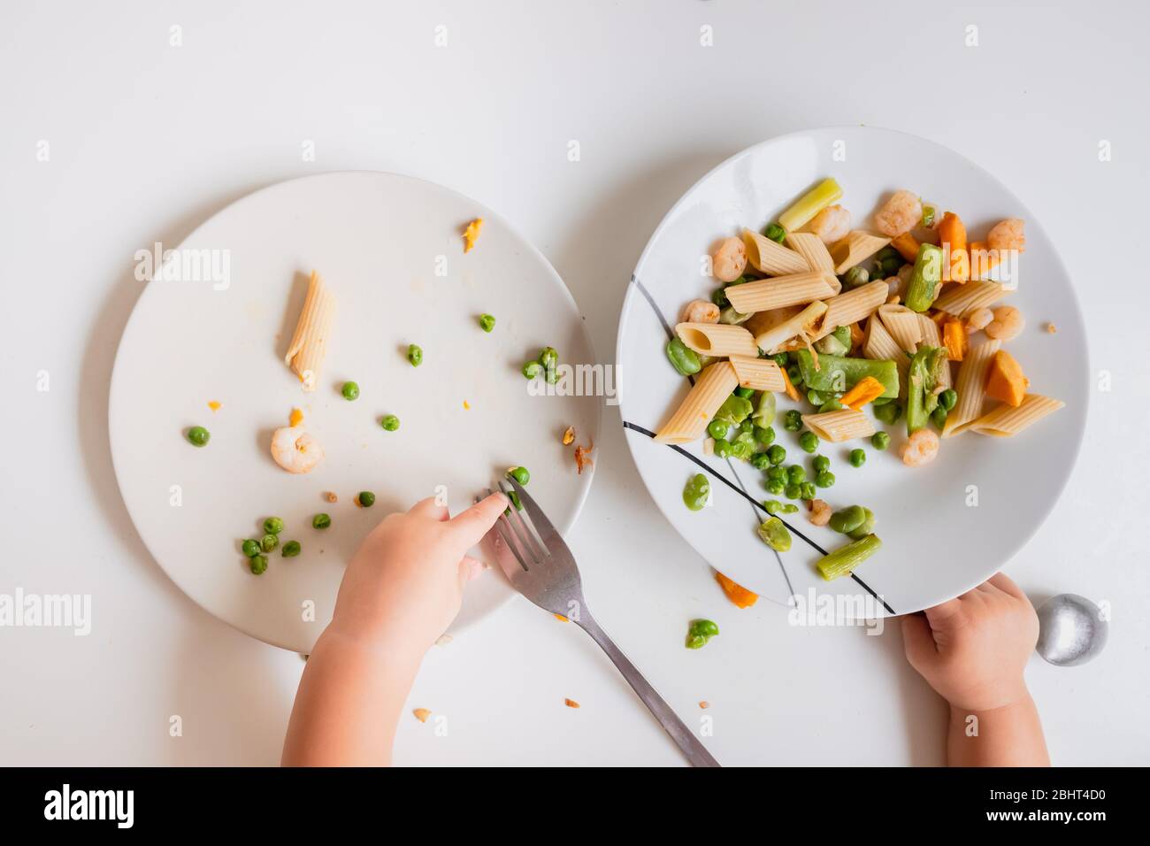 One-year-old baby eats the food from his plate directly with his hands ...