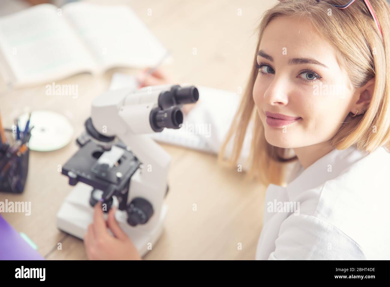 Beautiful young woman looking up to the camera while working with a ...