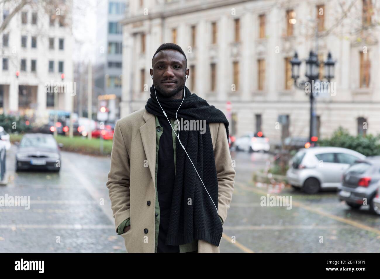 Handsome black real life model wearing beige coat with hands in pockets ...