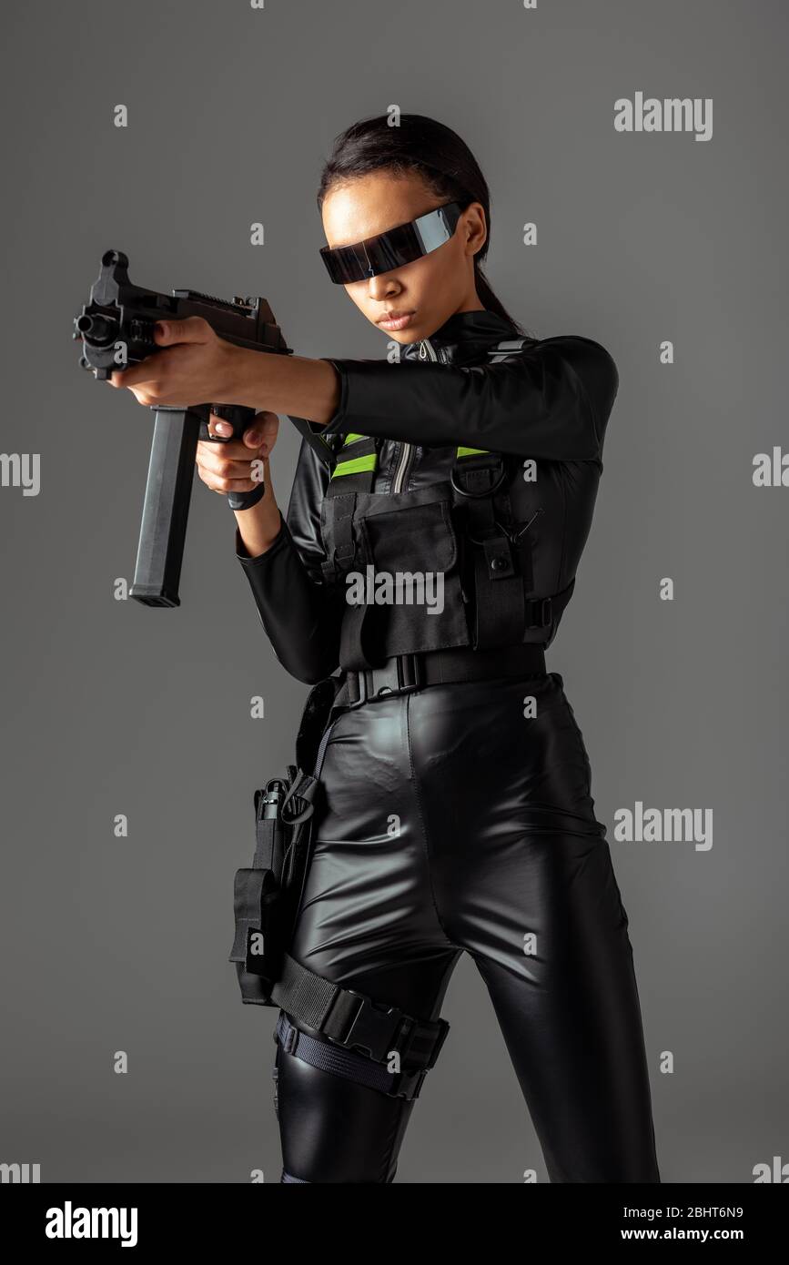futuristic african american woman in glasses aiming assault rifle ...