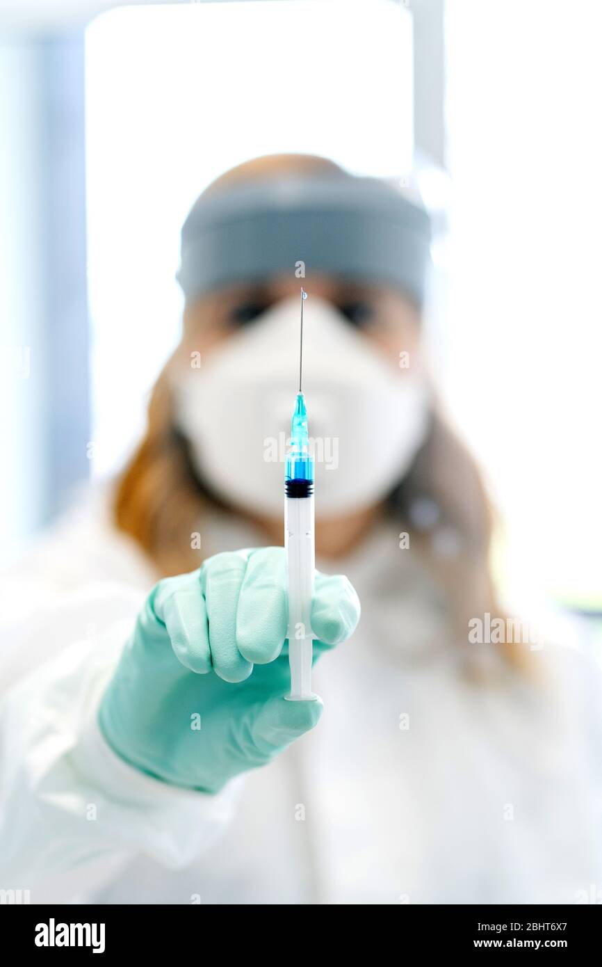 A hand picking up a syringe with latex protective gloves for safety ...