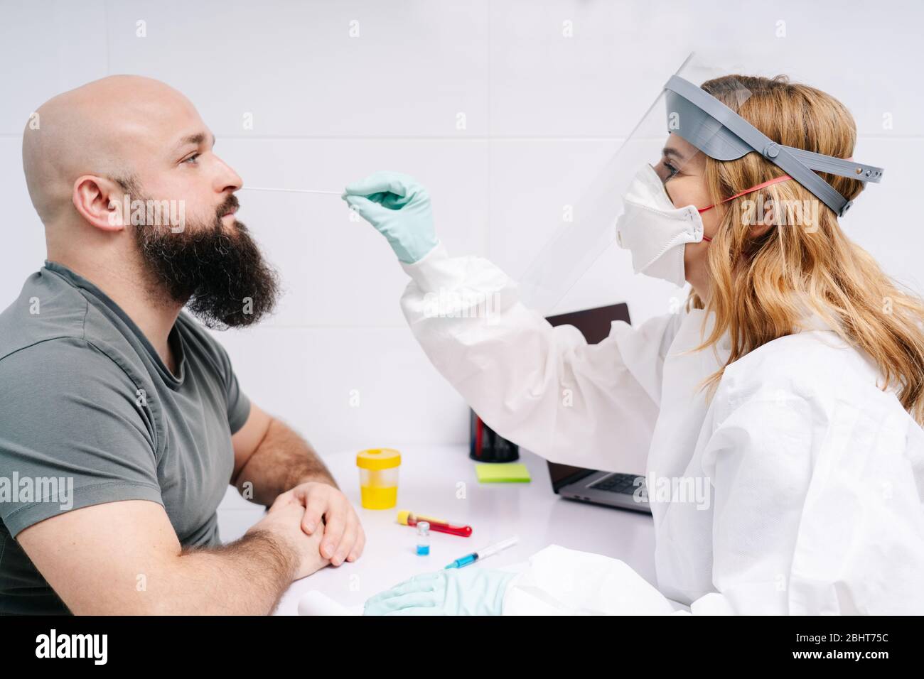 A female doctor does a swab test on a patient man in the hospital. She ...