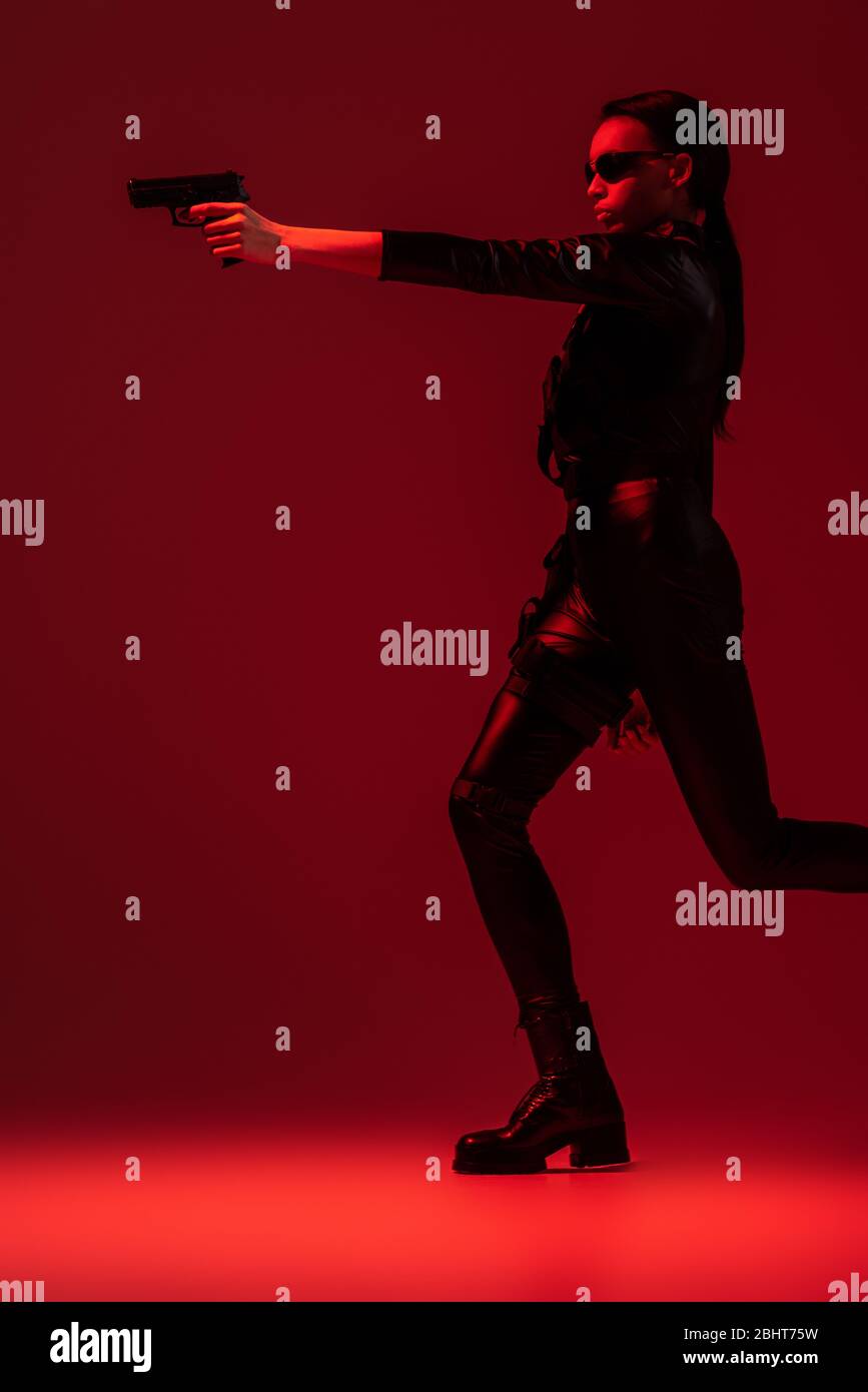 futuristic african american woman in glasses aiming gun on red ...