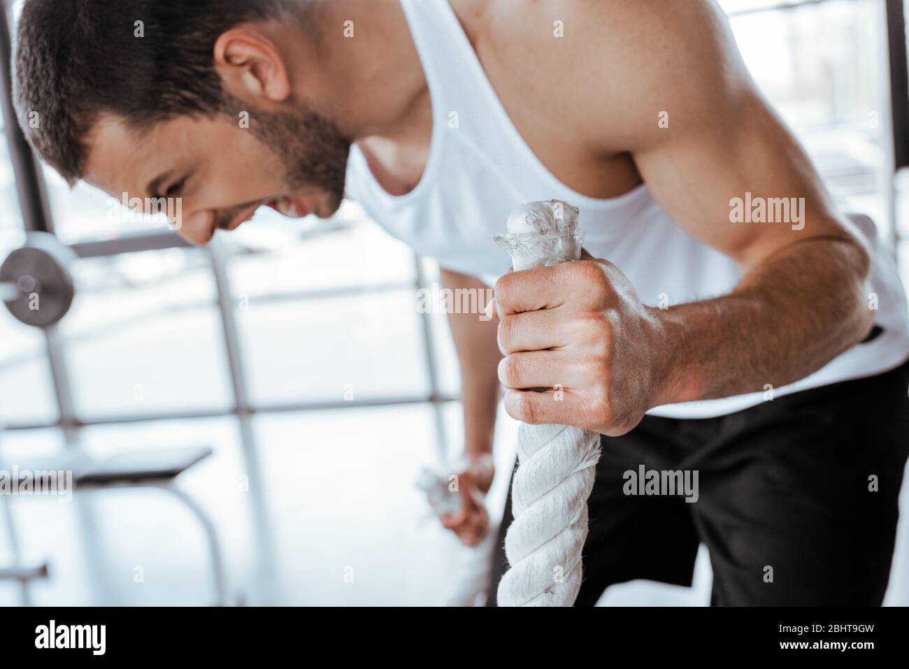 selective focus of emotional man screaming while exercising with battle ...