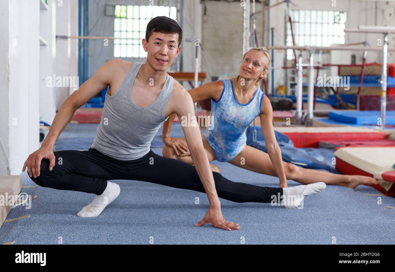 Mature sporty female and male acrobats during workout in sport gym ...