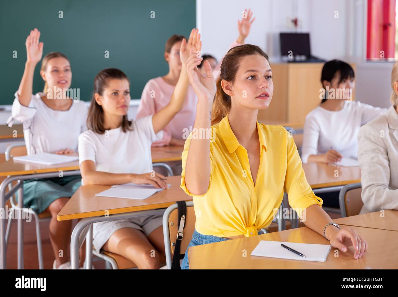 Portrait of multinational students group raising hand to answer during ...