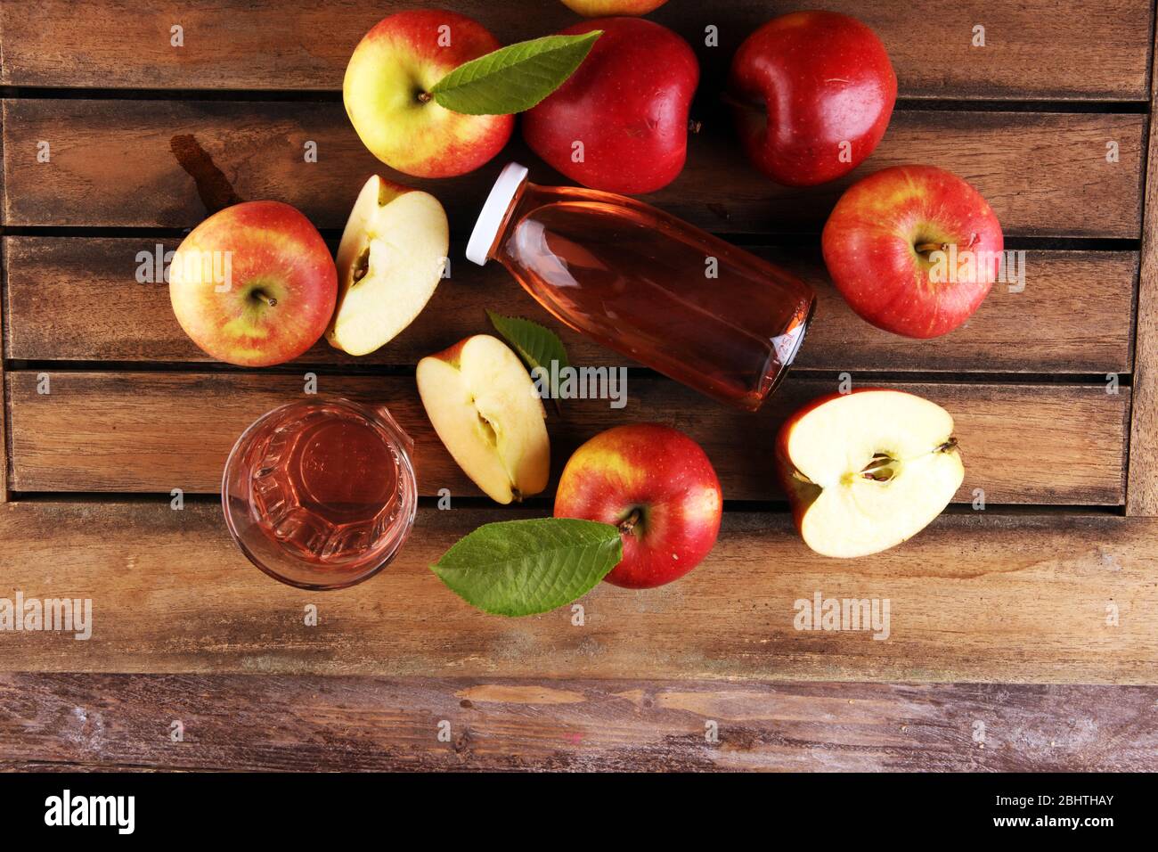 Apple cider drink and apples with leaves on rustic table Stock Photo ...