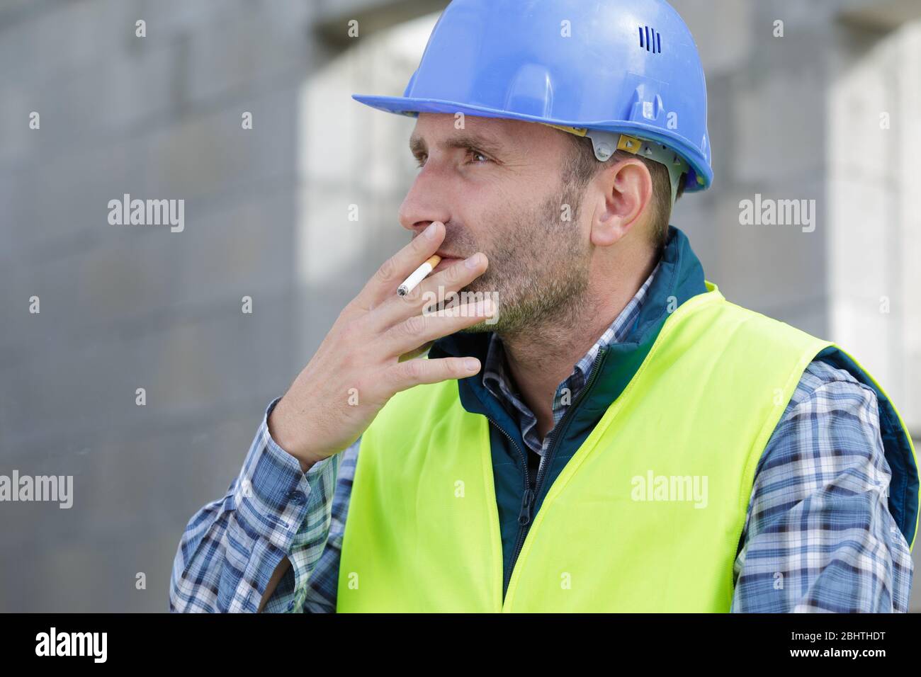 happy builder smoking cigarette on construction site Stock Photo - Alamy