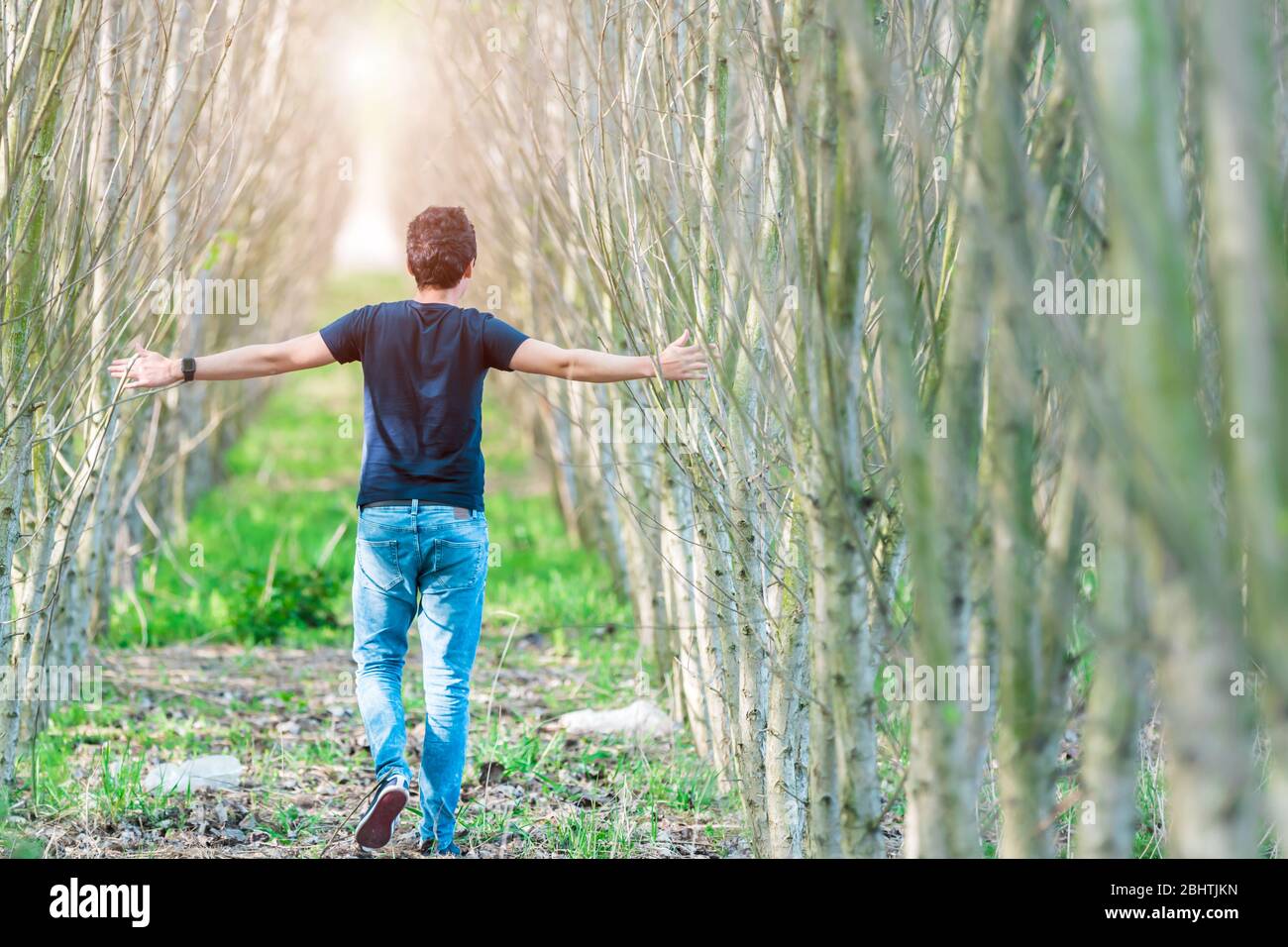happy man running on a forest path opposite the sun. hands touching a ...