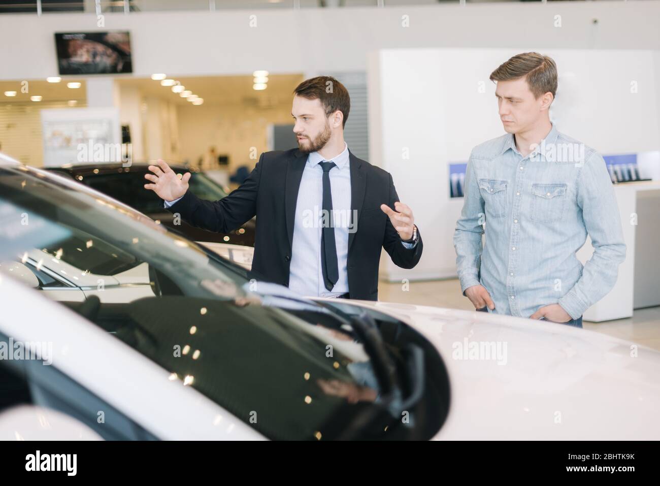 Professional car salesman wearing suit is telling interested buyer ...
