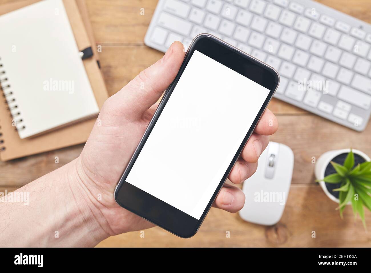 Man holding a phone with isolated screen over the desk in the office ...
