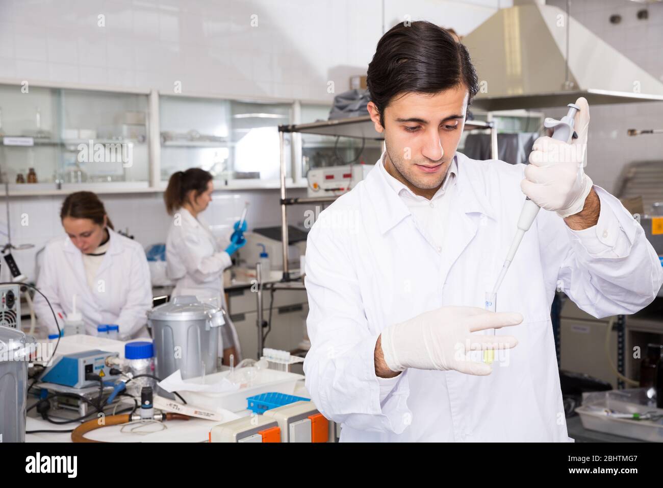 Professional chemist working in laboratory, mixing reagents in test ...