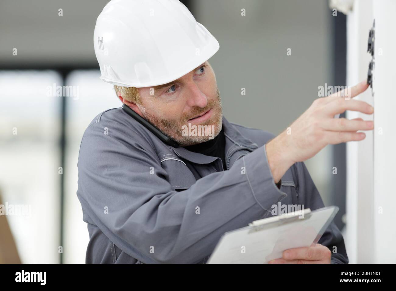 technician pressing switch smartphone balanced between ear and shoulder ...