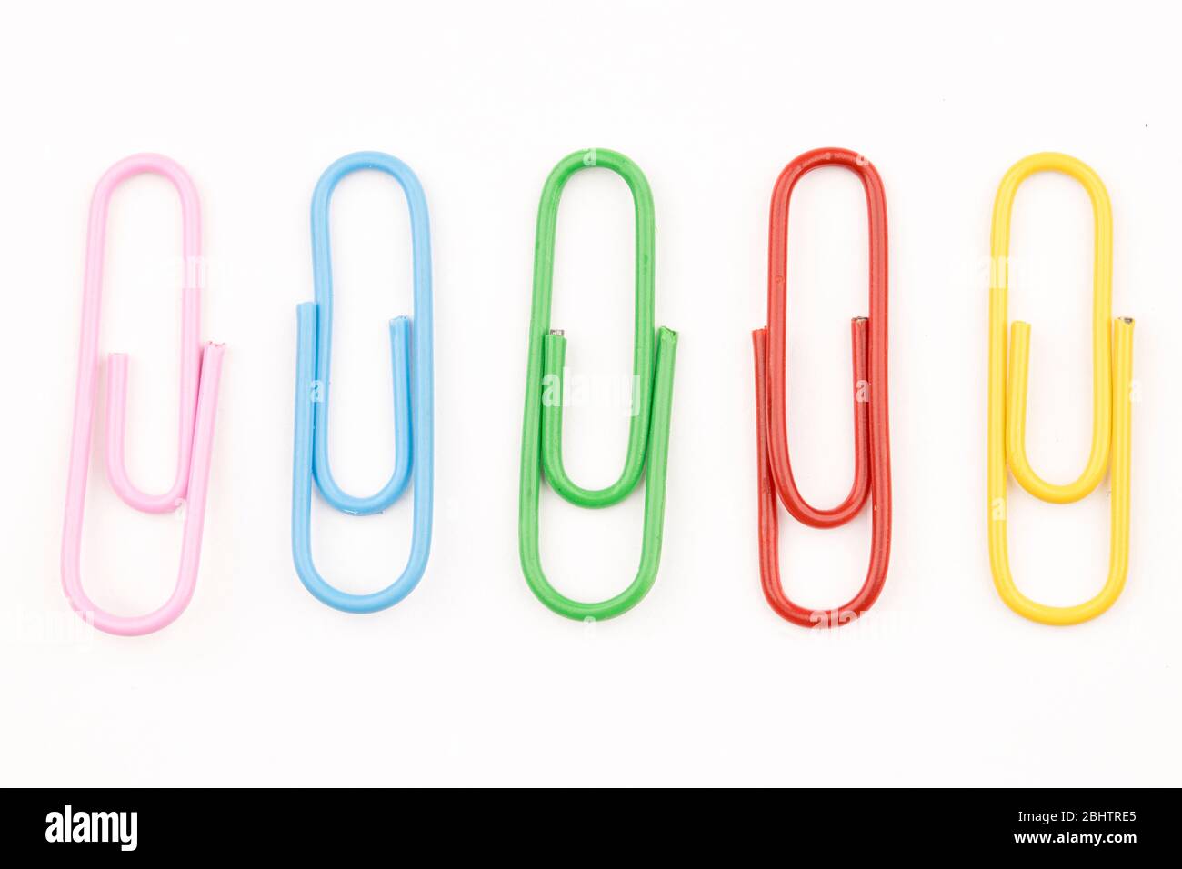 A concept photo of multi-colored paper clips on a white background ...