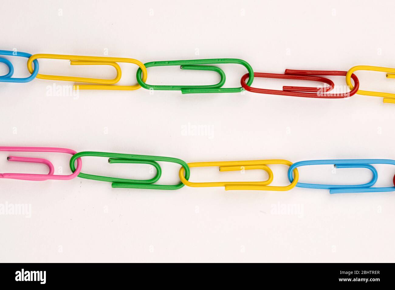 Concept of two links of multi-colored paper clips on white background ...