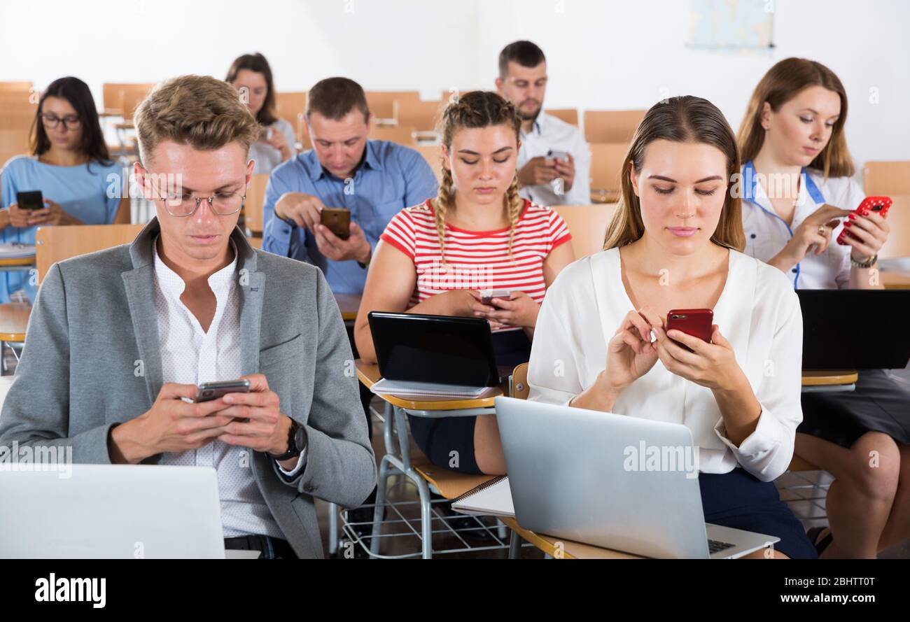 Young people using social media while studying in university auditorium ...