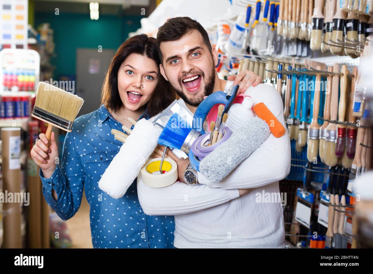 Happy couple purchasing tools for house improvements in paint supplies ...