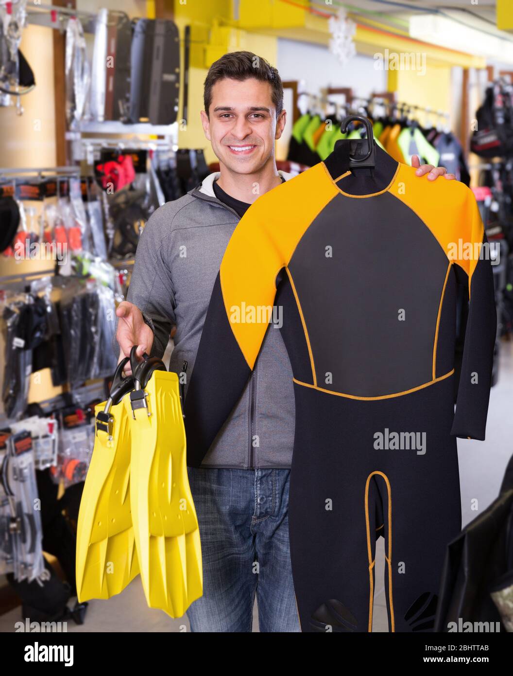 Man is standing with modern diving costumes and flippers in the store ...