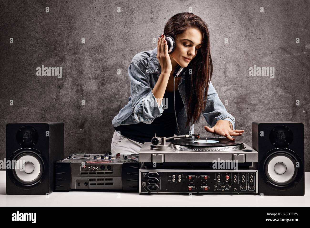 Female dj playing music on a turntable against a rusty gray wall Stock ...