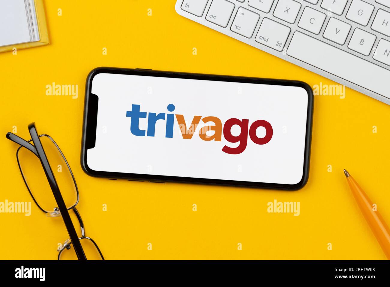 A smartphone showing the Trivago logo rests on a yellow background ...